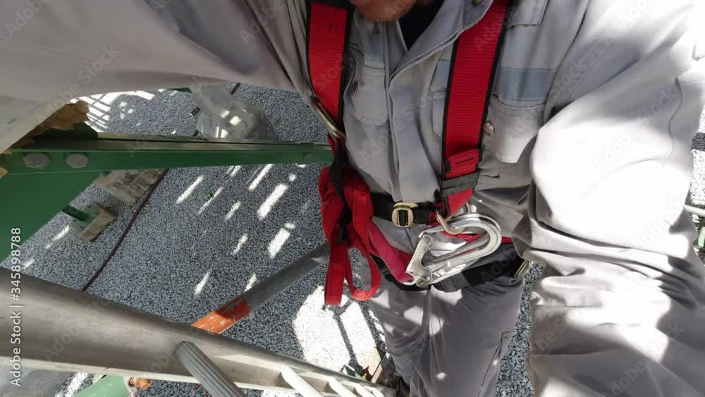 A worker wearing a safety belt climb on a ladder for working at height ...