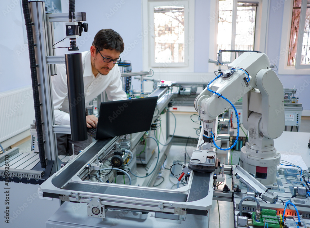 Close-up robot arm. Engineer is working on laptop to programming smart ...