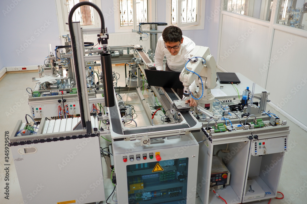 Close-up robot arm. Engineer is working on laptop to programming smart factory automation and ...