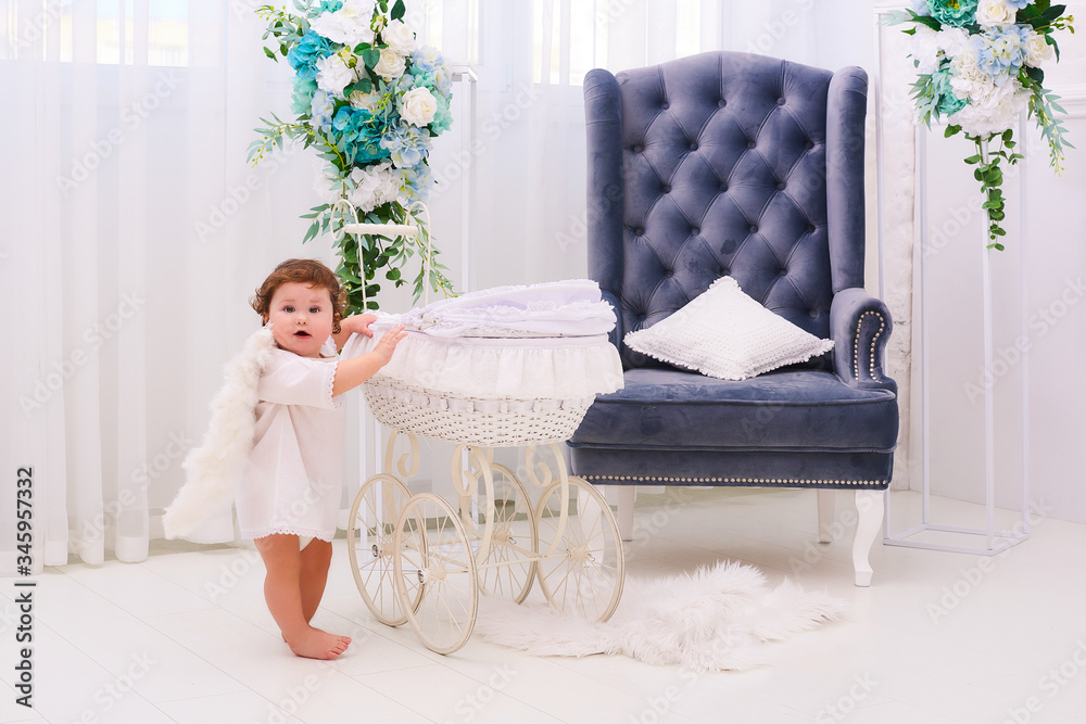 Little boy like angel smile and stand near white buggy. Toddler boy in ...