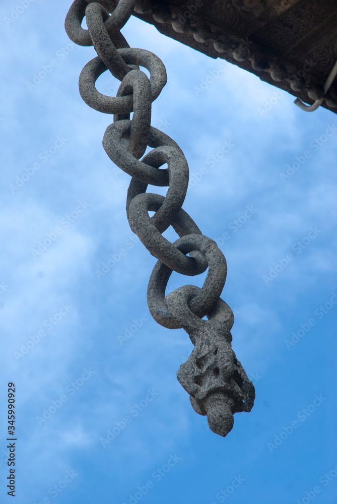 chain made of single stone is hanging at the corner of a building ...