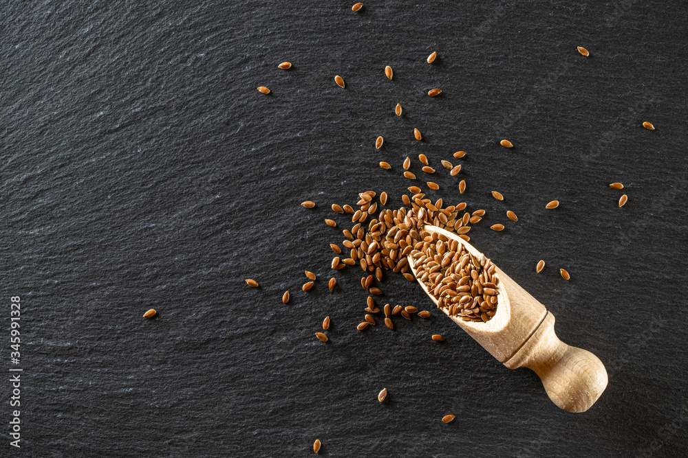 Linen seed, flaxseed - organic food background. Brown flax, linseed in wooden scoop for oil ...