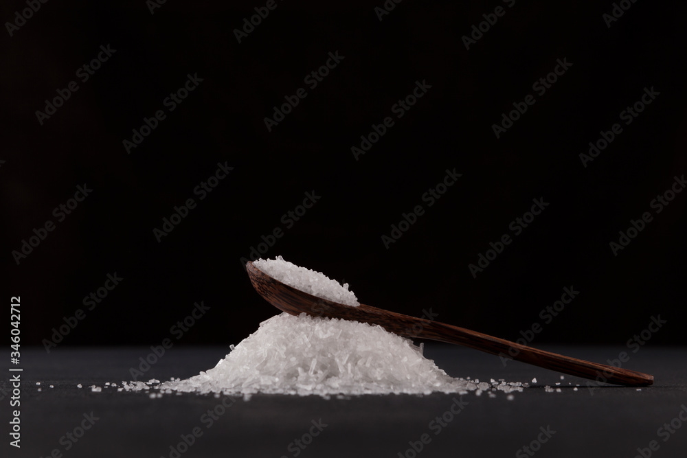 Glutamic acid monosodium salt in a wooden spoon on a dark background ...