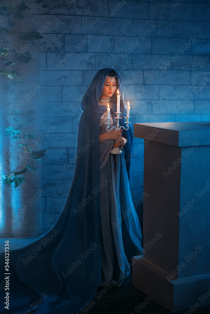 young woman queen stands in dark night room mysterious castle. Lady elf princess holding ...