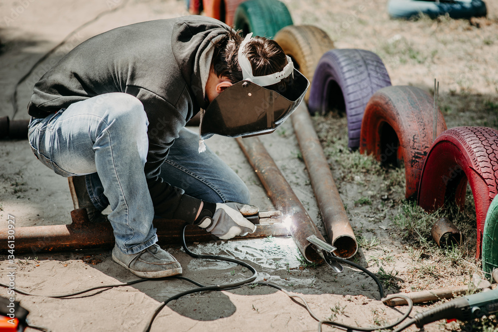 Welder in a welding mask electrically welds a metal structure Stock ...