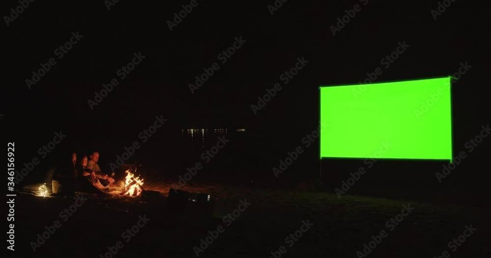 Outdoor cinema. Friends gather in a campfire camp and watch a movie ...