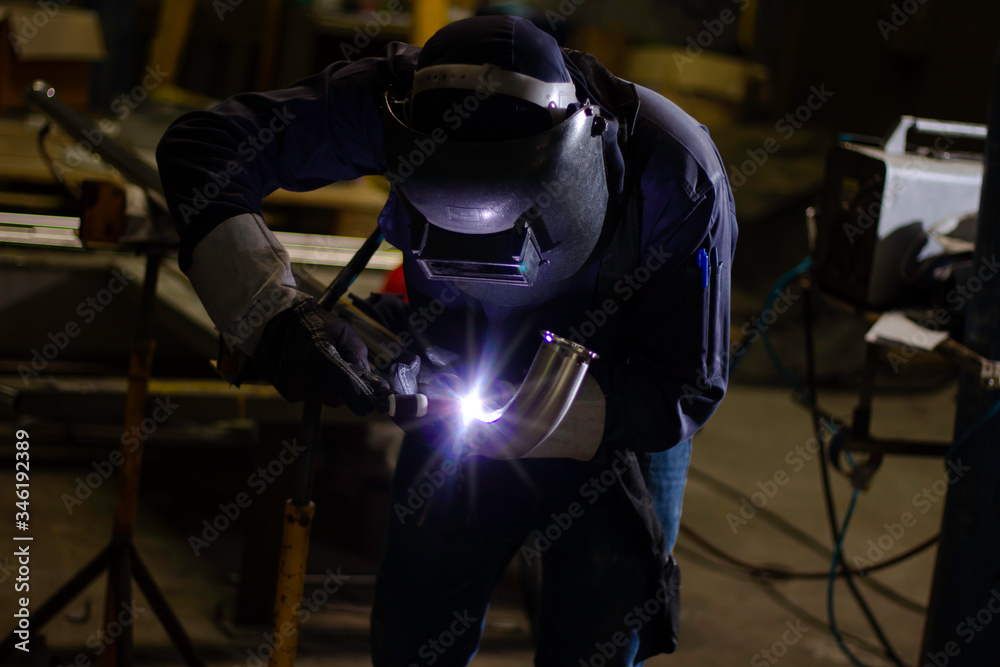 Welder is welding the steel in the factory. Weld the steel in dark ...
