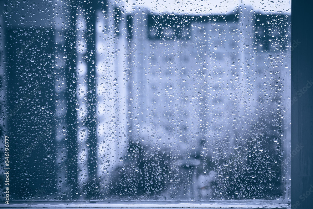 rainy droplets on a blue window glass transparent surface. drops on ...