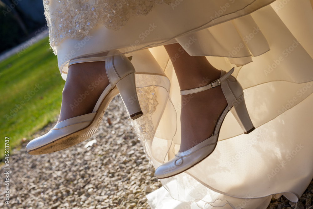 A bride sitting on a chair outside, at the bride's feet there are ...