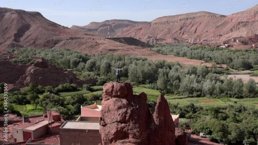 Young man dancing with open arms on the top of old red cliff in the ...