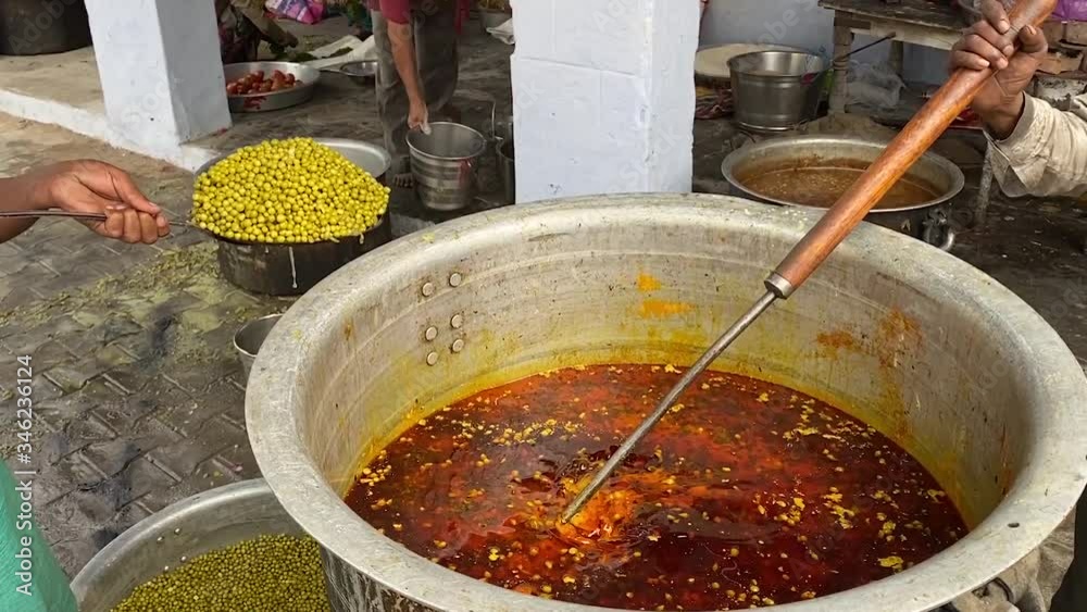 throwing beans into a big iron cooking pot full of spice and red chile ...