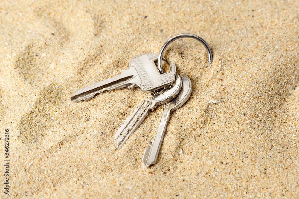 Ring with three home keys on a sea sand. Forget or fall house keys ...