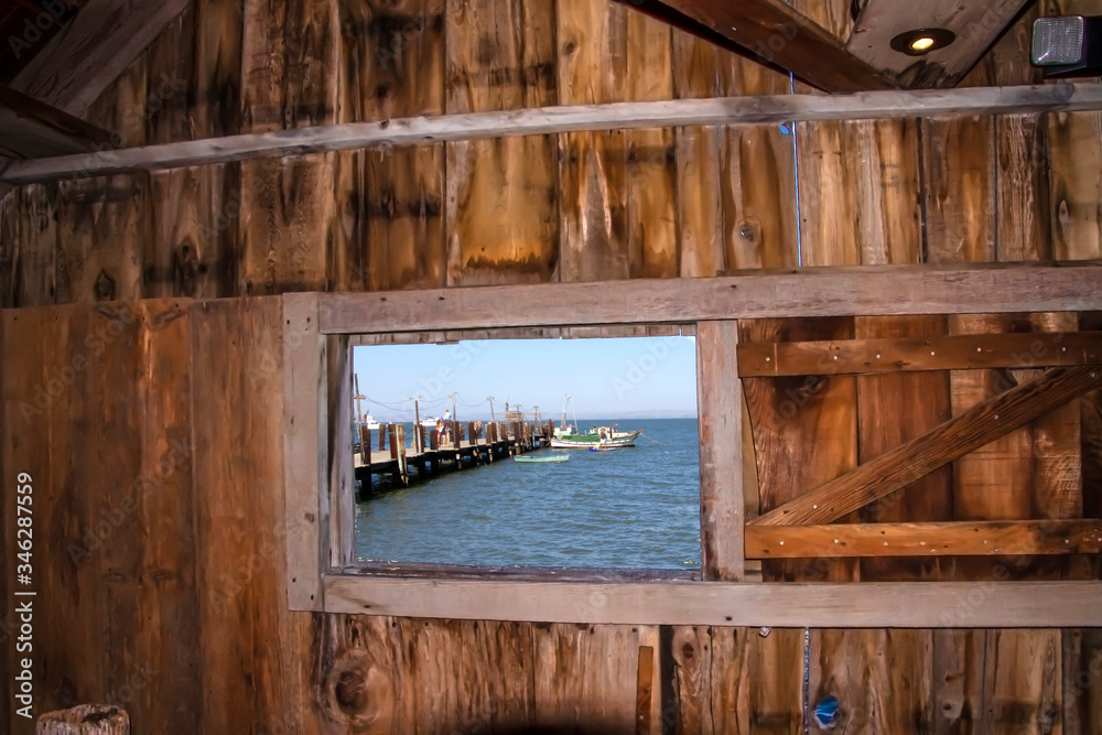 Blue ocean view with a pier and a boat from seen through a window ...
