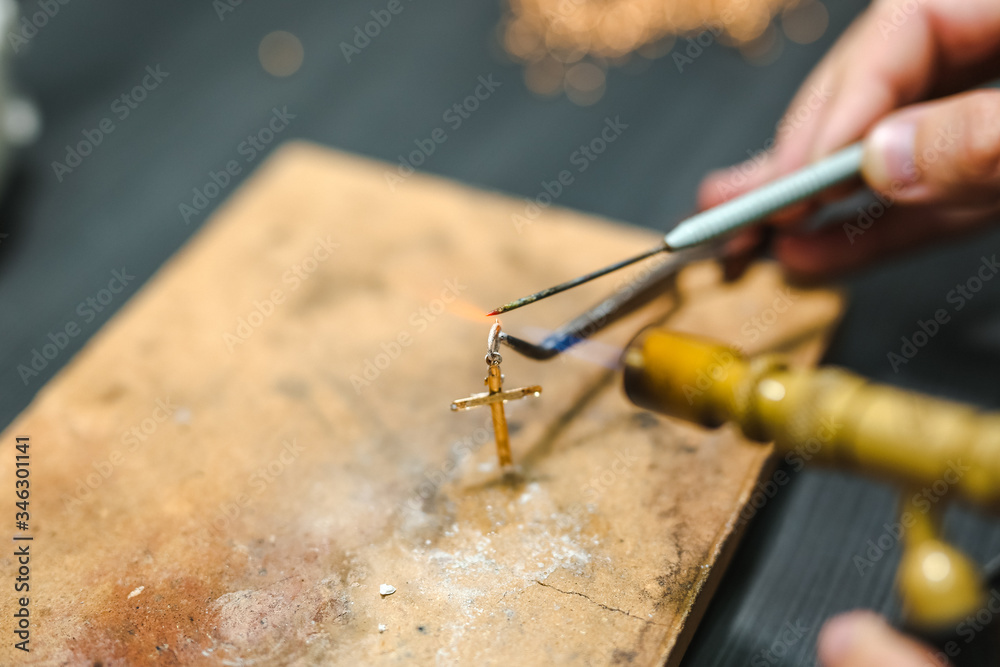 Master goldsmith while working jewelry of gold cross on the of work ...