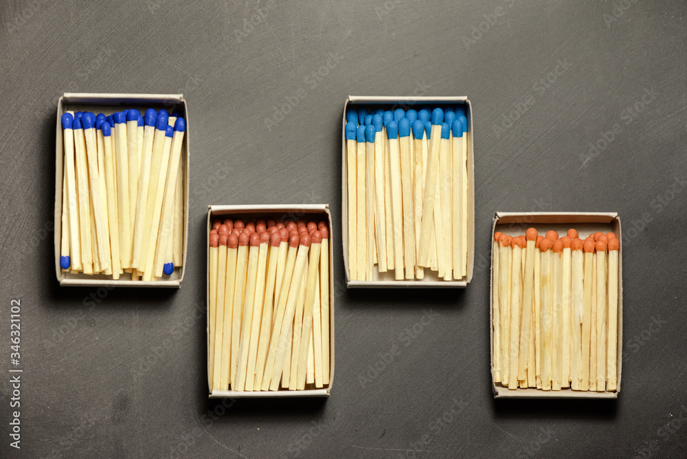 Matches of different colors in cardboard boxes on gray board. Boxes are ...