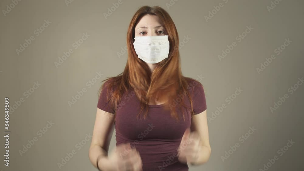 Masked caucasian redhead woman with red hair and shirt putting mask ...