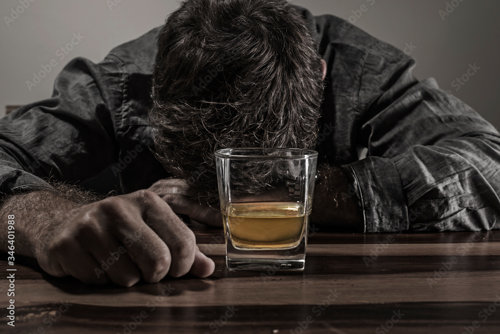 Foto de young messy and drunk alcohol addict man drinking whiskey glass at home sitting ...