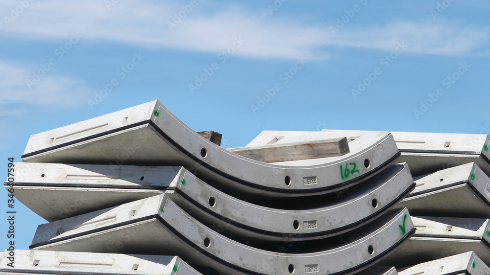 Curved pre cast concrete interlocking tunnel segments stacked. Blue sky ...