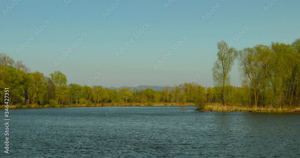 Zoomed out movement moving lake surface during sunny spring day during strong wind around lots ...
