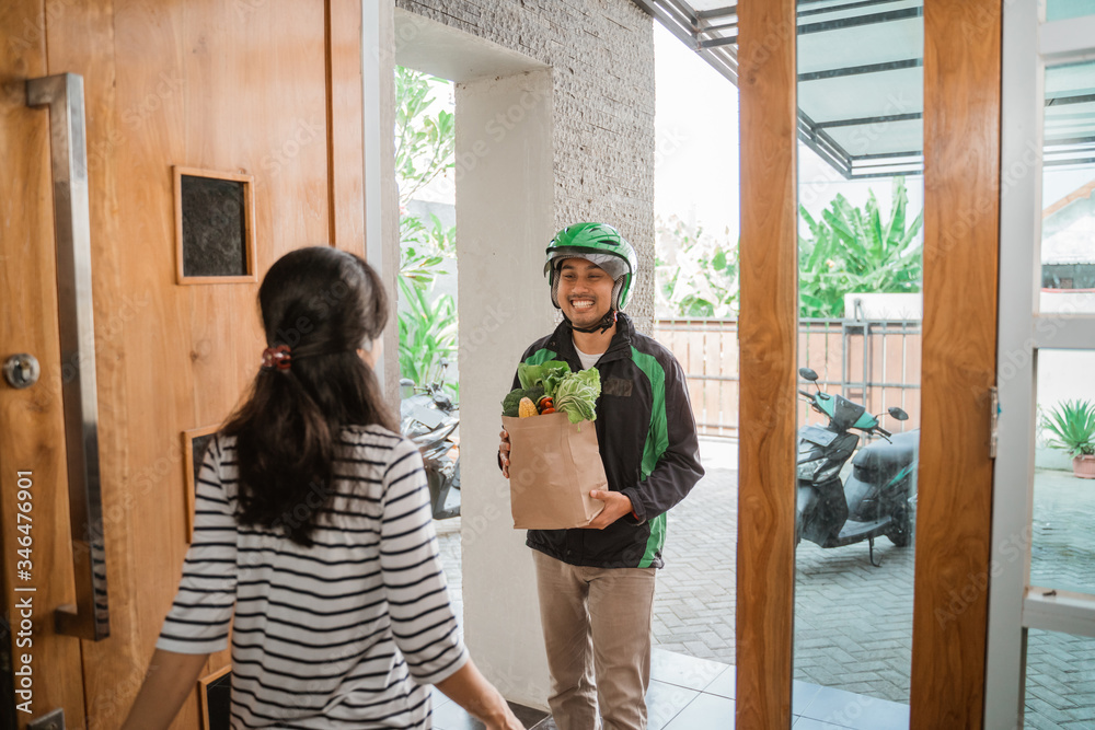 delivery boy is delivering some groceries to woman. He is handing her a ...