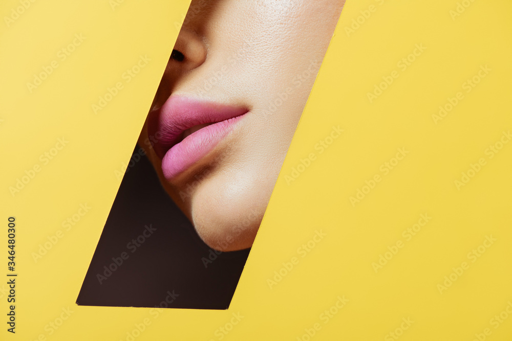 Partial view of female face with pink lips in quadrilateral hole in ...