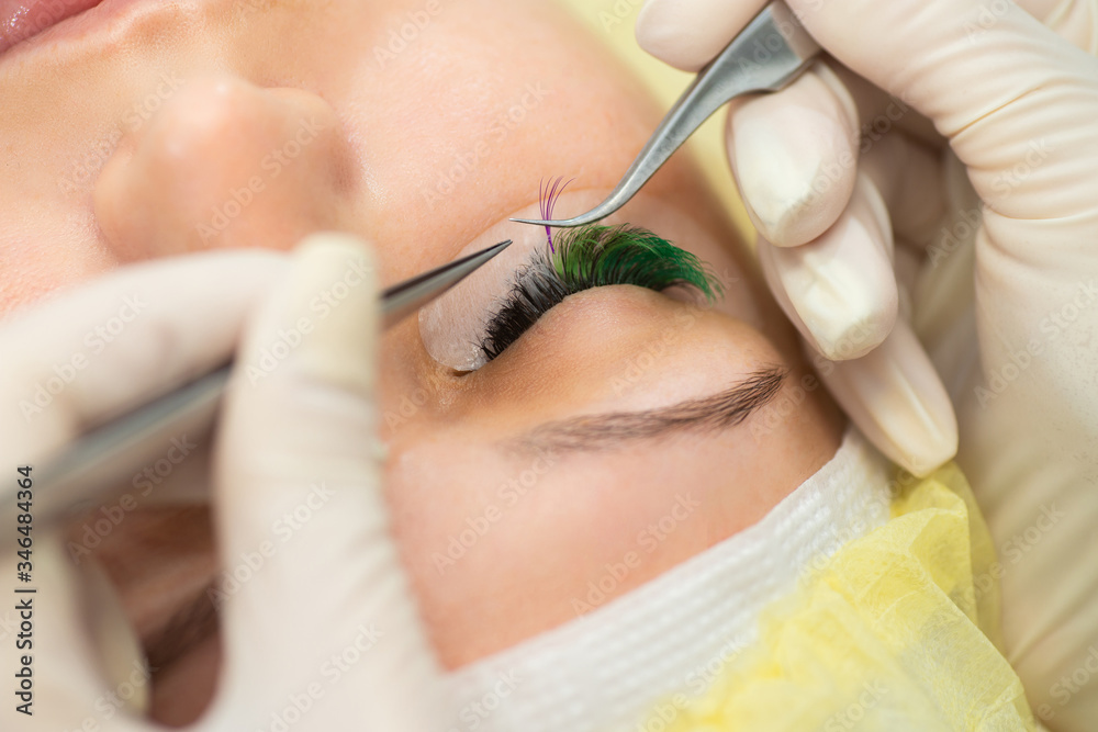 The master builds up large colored eyelashes to the client. Preparation ...
