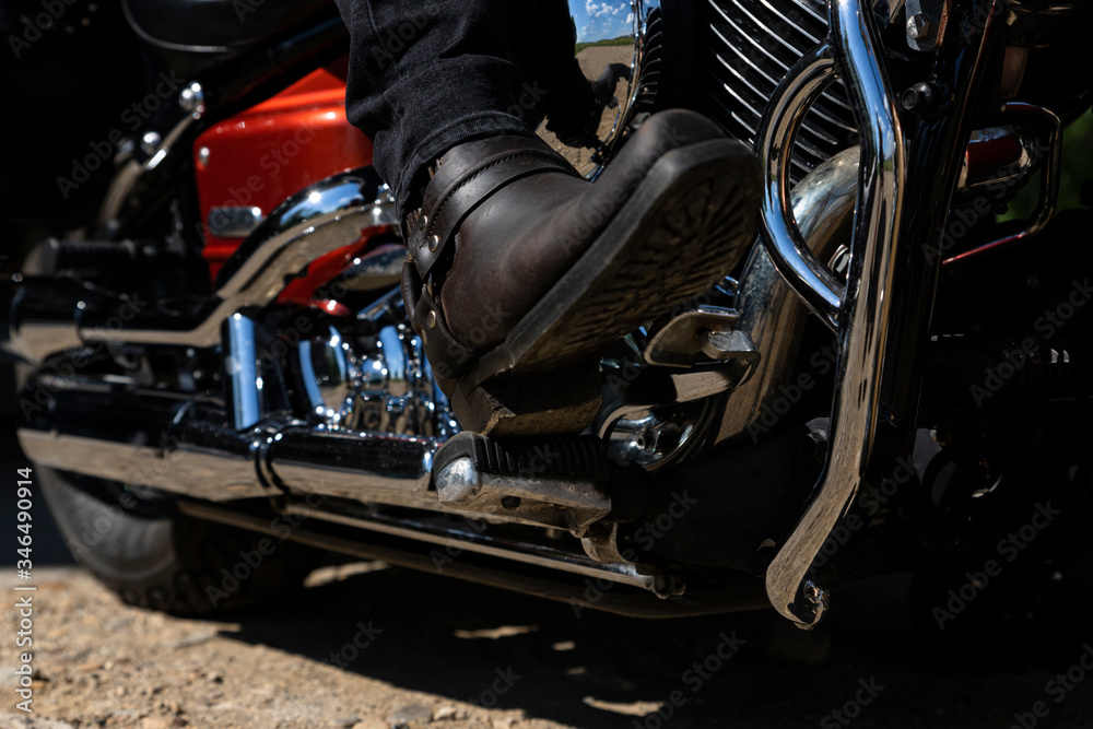 Biker riding a motorcycle. Bottom view of the legs in leather cowboy ...