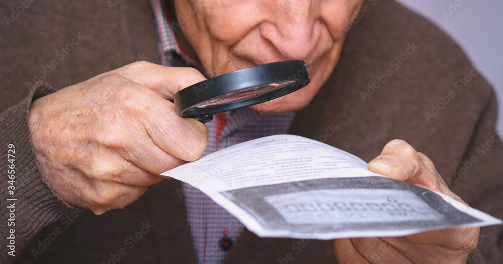 old man with low vision reading text with magnifying glass Stock Photo ...
