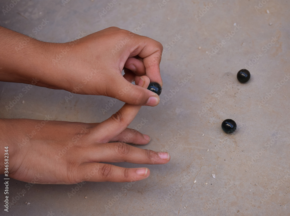 Indian Childhood games - Child playing with glass marbles which is an ...