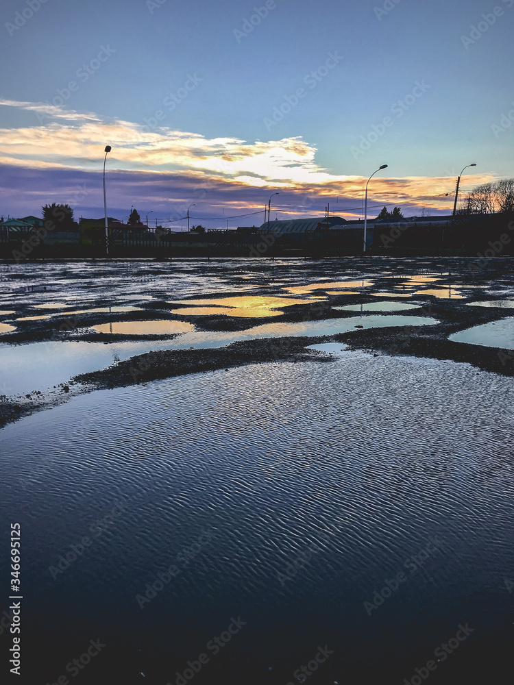 Rain puddle with wind pattern and reflection on the ground with rural ...