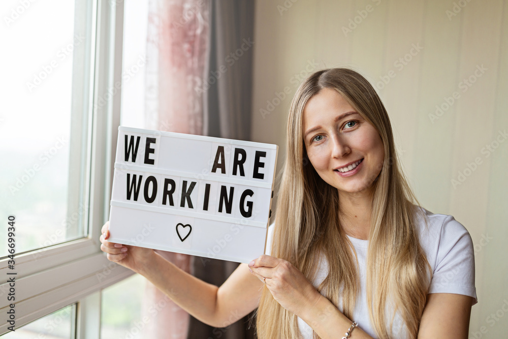 Woman holding lightbox with text we are working. End of covid-19 ...