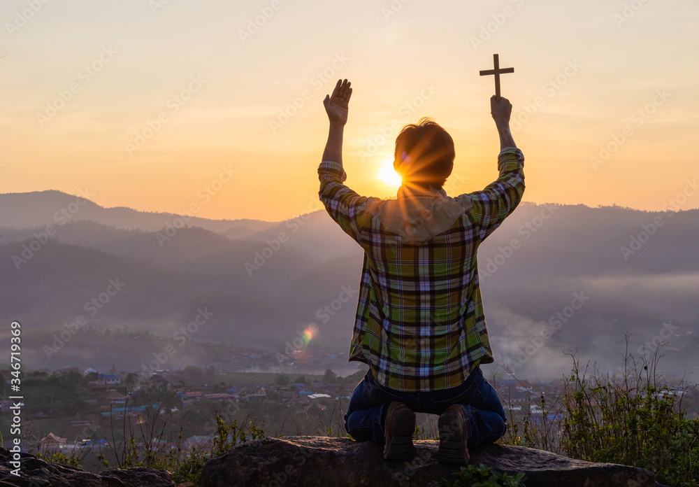 Human kneeling down praying and holding christian cross for worshipping ...
