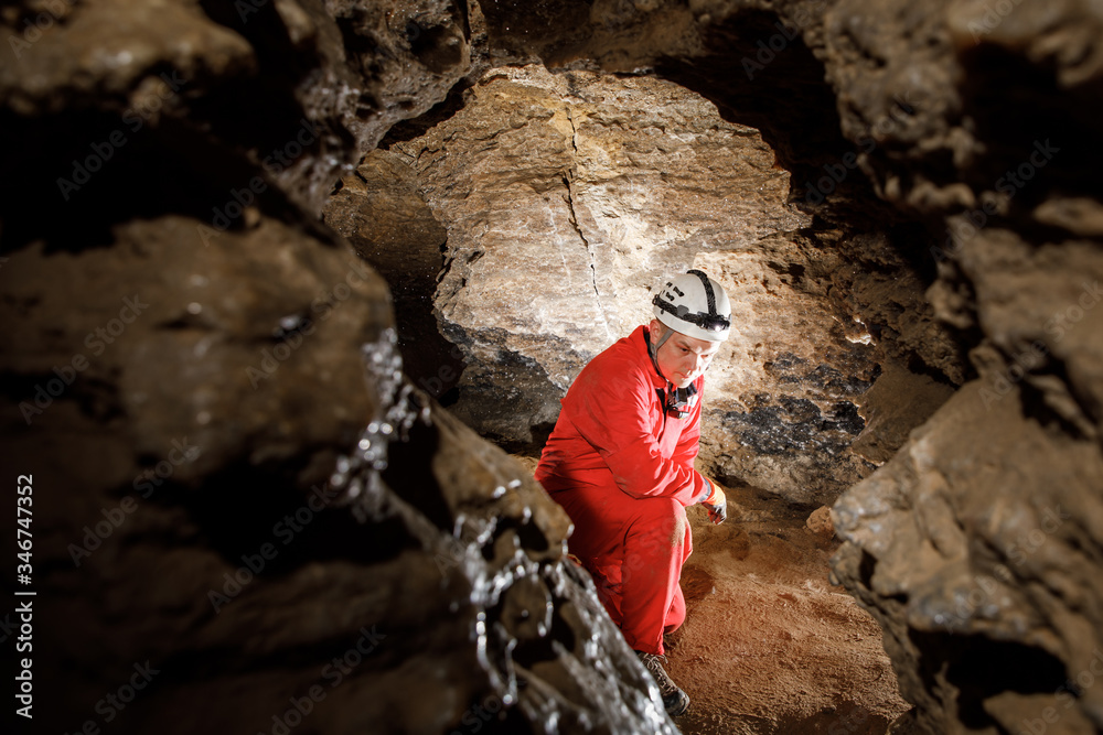 Man walking and exploring dark cave with light headlamp underground ...