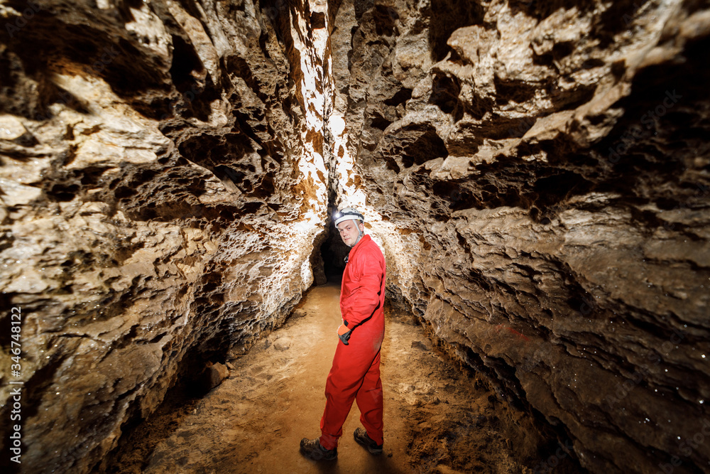 Man walking and exploring dark cave with light headlamp underground ...