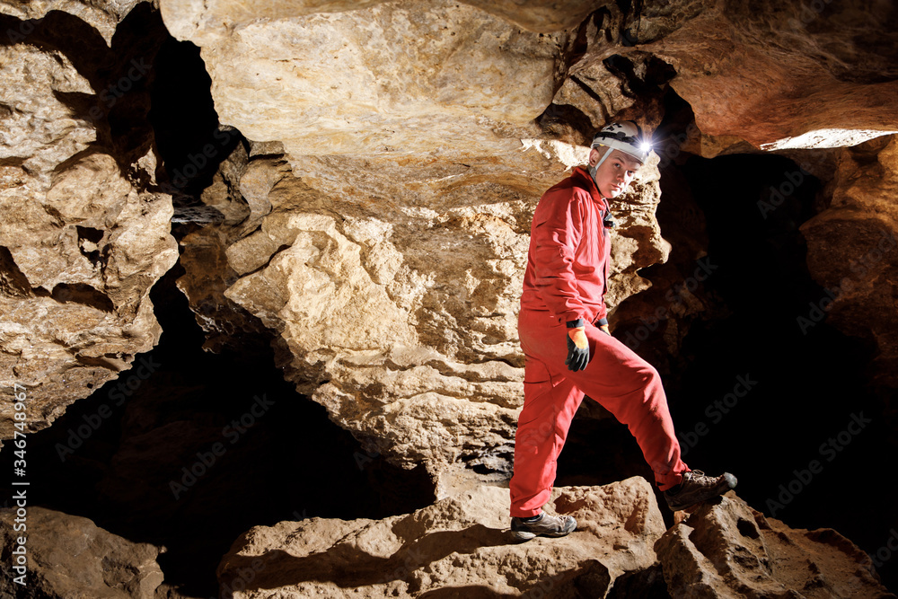Man walking and exploring dark cave with light headlamp underground ...