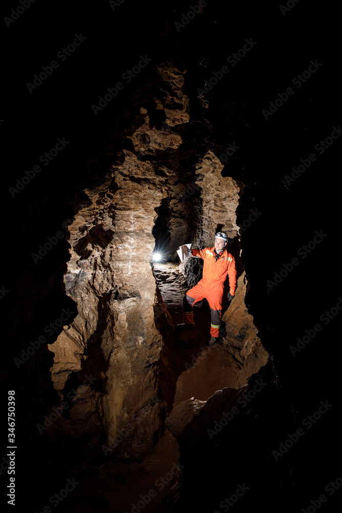 Man walking and exploring dark cave with light headlamp and map in his ...