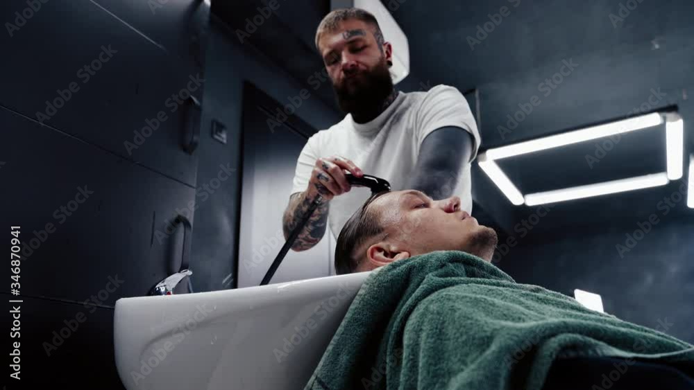 Attractive male is getting a modern haircut in barber shop. Top view of ...