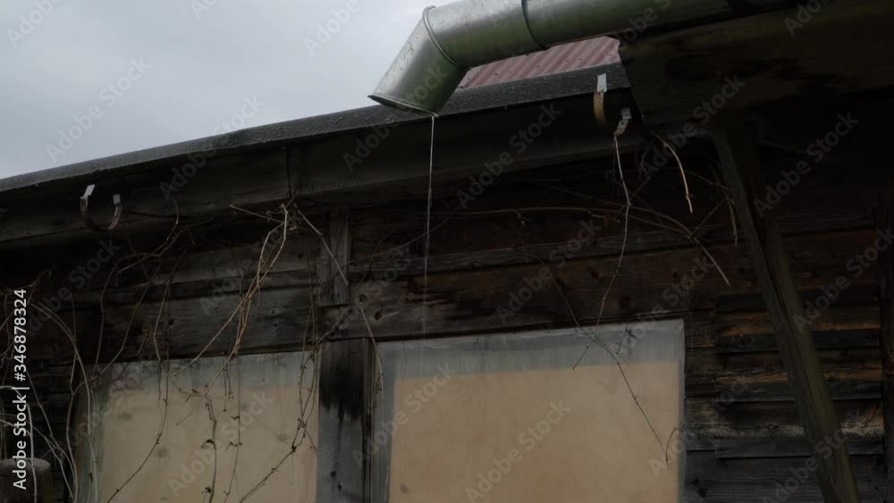 A stream of water flows from the drainpipe of an old village house ...