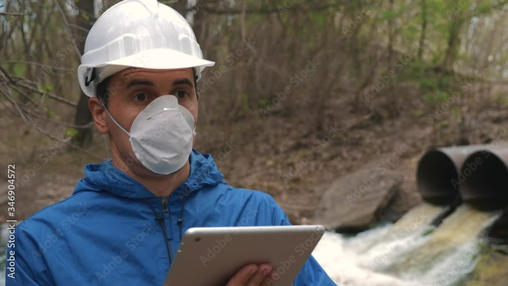 A human ecologist, an engineer wearing a helmet and a respirator, uses ...