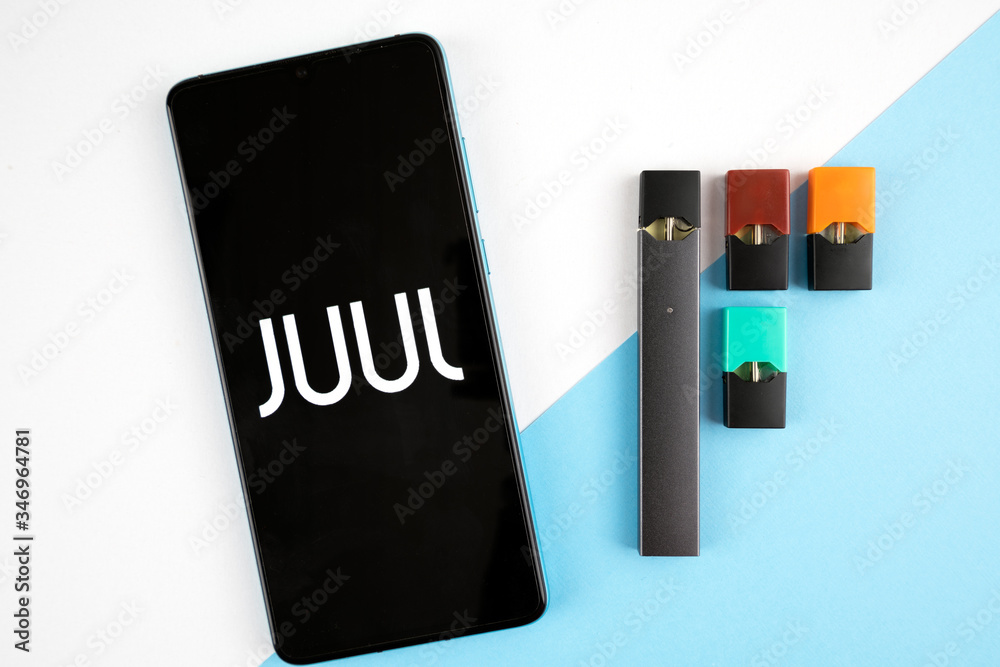 Juul vaping device next to flavored and colored vaping pods. Juul logo ...