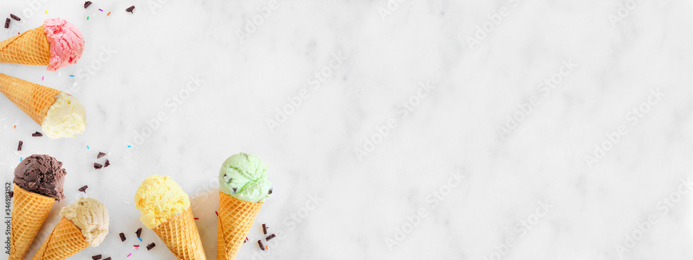 Ice cream cone corner border with a variety of flavors. Top view over a ...