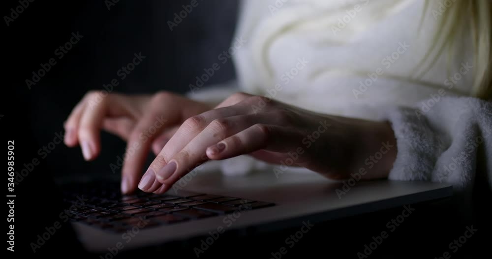 girl typing message on a laptop, in the dark. Fingers running on ...