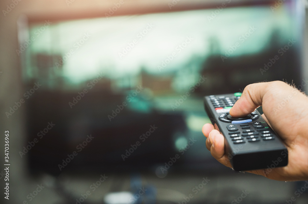 Young man holding television remote control. Hands pointing to tv ...