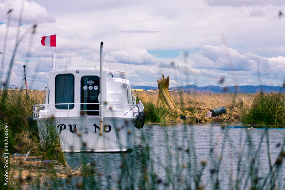 White boat with the Peruvian flag on Lake Titicaca, a floating city of ...