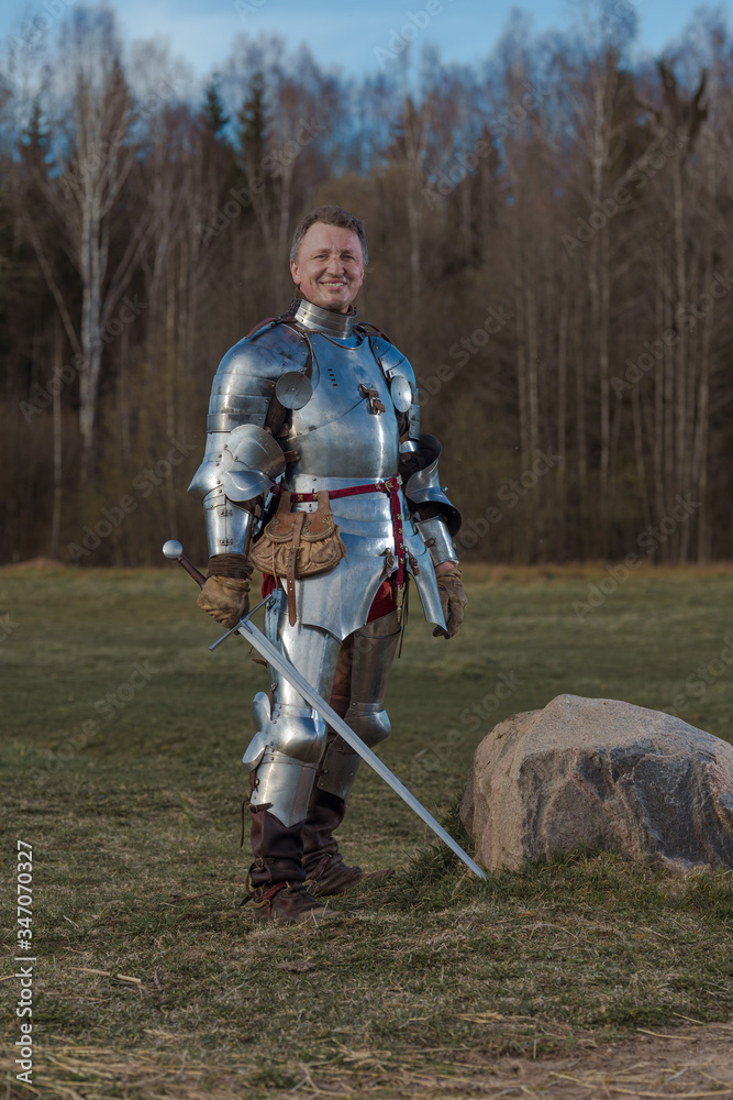 A knight on foot in armor and holding a sword in his hands shows combat ...
