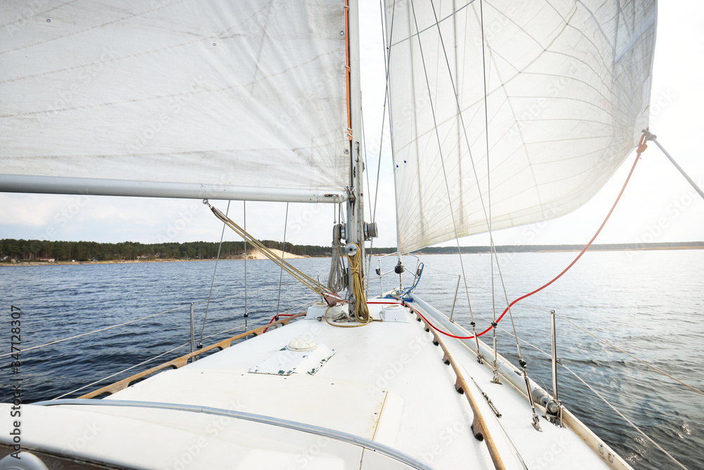White yacht with full sails running downwind wing-on-wing, sailing ...