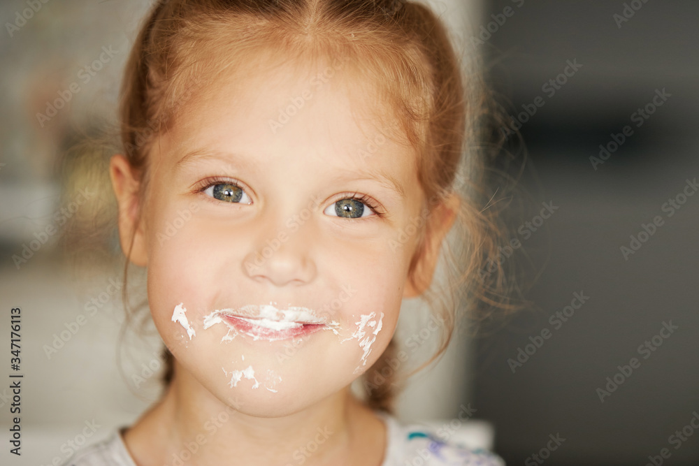 Cheerful smiling child girl eating a delicious cake and showing thumbs ...