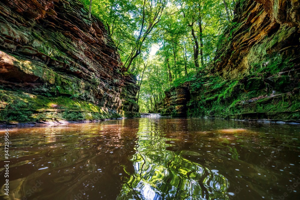 A hidden ravine with a small shallow stream flowing between rock walls ...