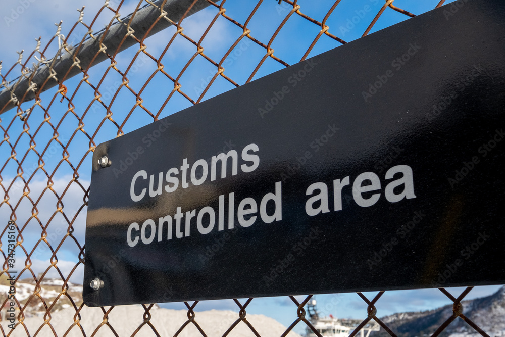 Black sign with white letters spelling customs controlled area. The ...