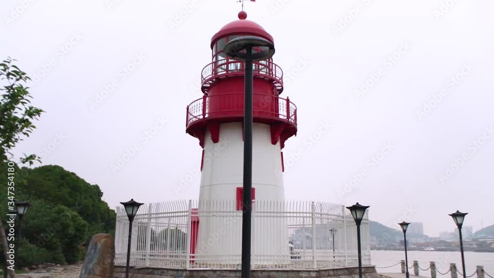 The lighthouse along the river near the estuary surrounded by bushes ...